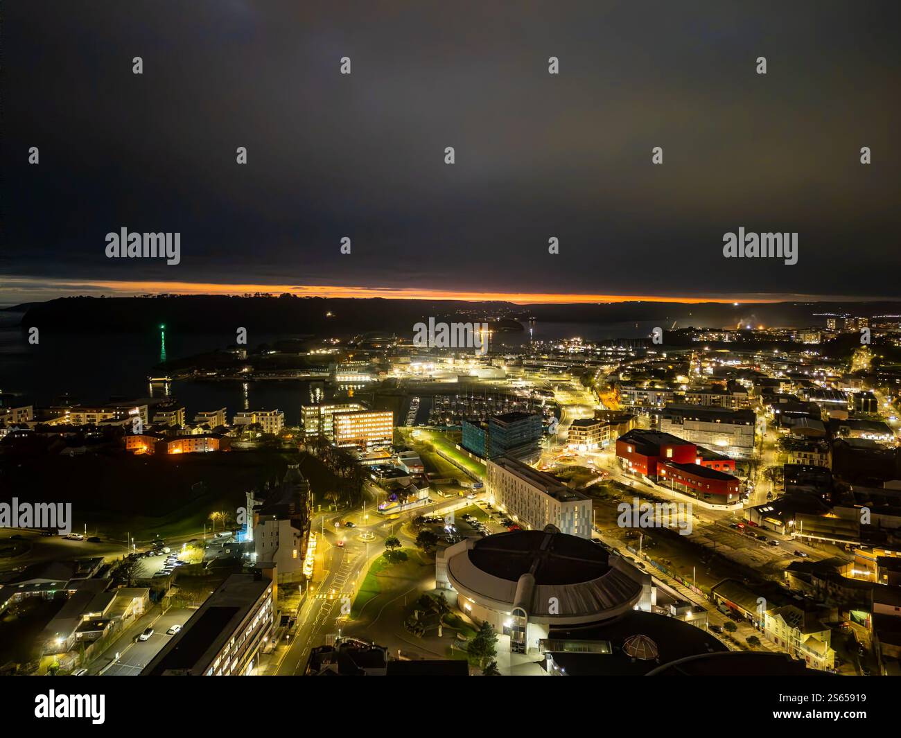 Aerial view of Plymouth city center and harbor glowing at sunset, with ...