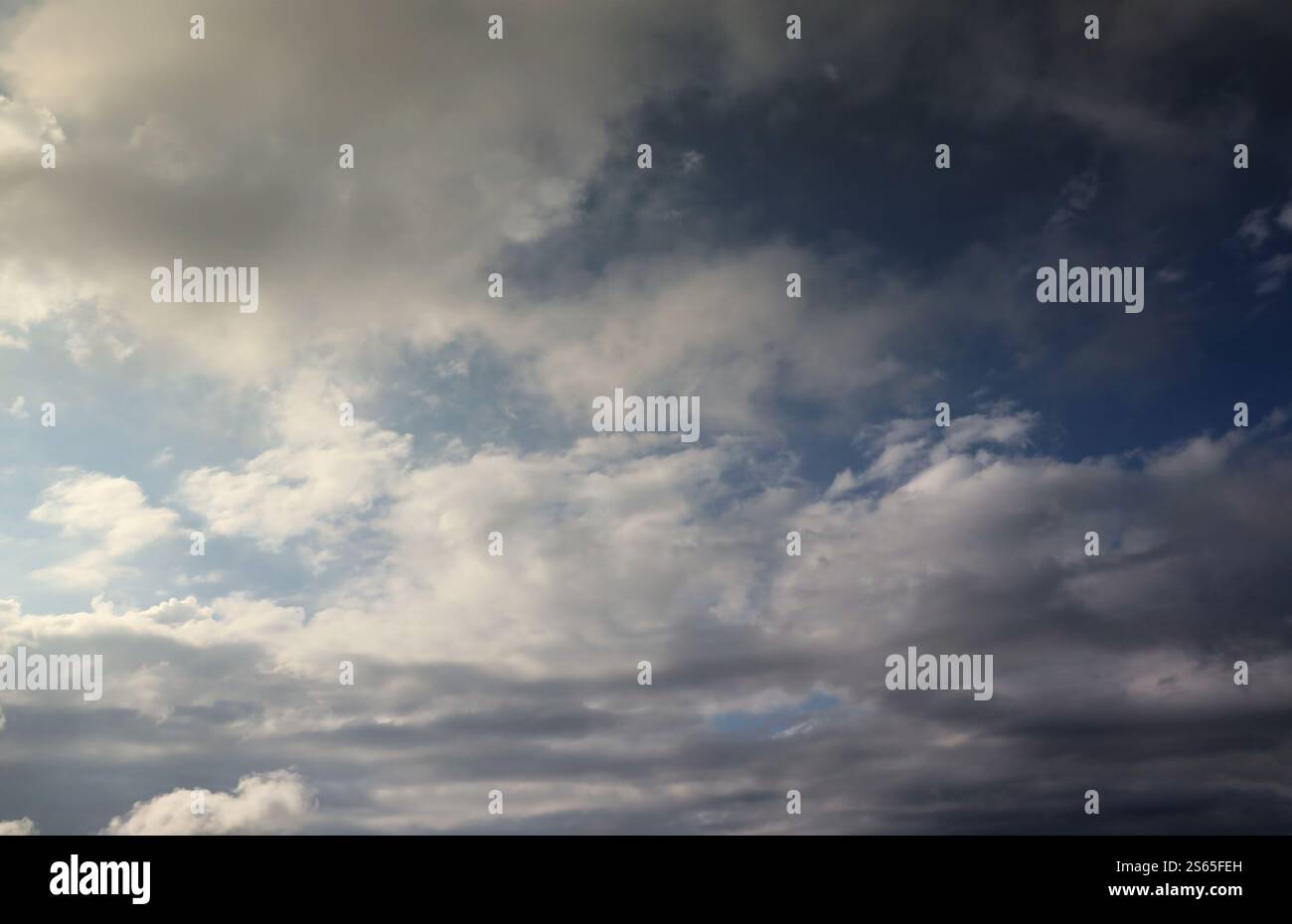 Beautiful cloud formations in the sky with sunlight behind. White clouds on dramatic blue sky at ...