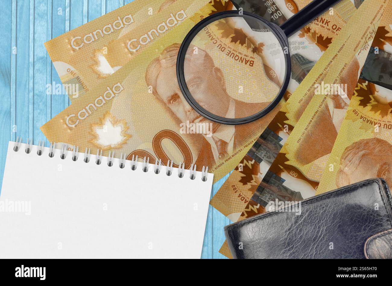 100 Canadian dollars bills and magnifying glass with black purse and ...