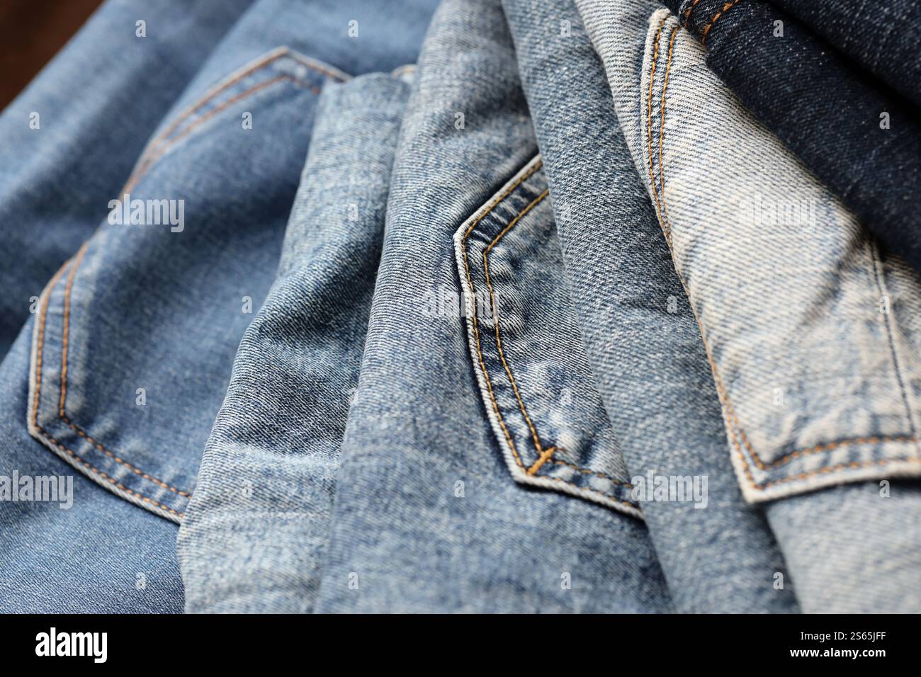 Many jeans in stack in wardrobe room. Row of pants denim jeans in ...