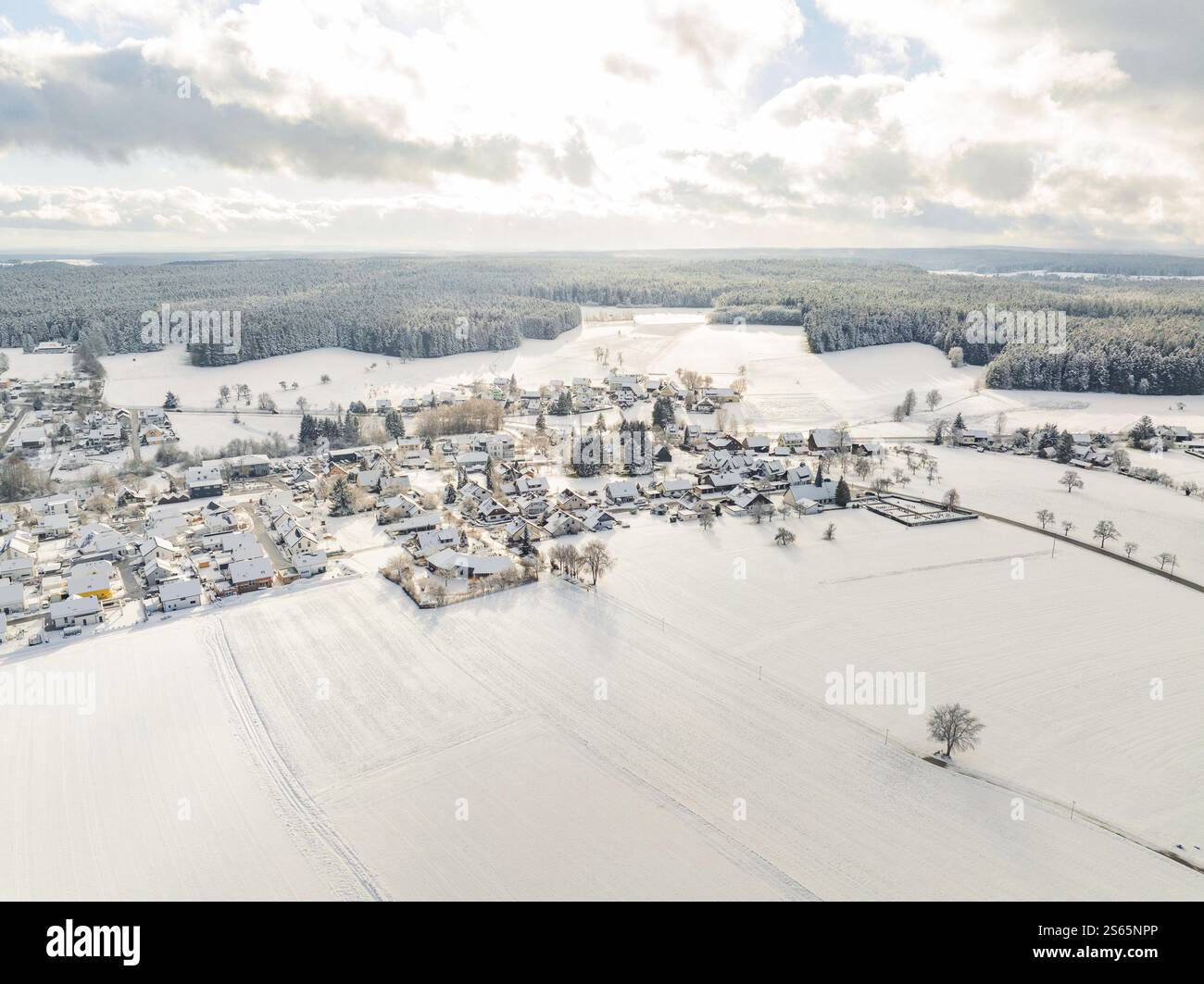 Snow-covered village in a wide landscape with blue sky and clouds ...