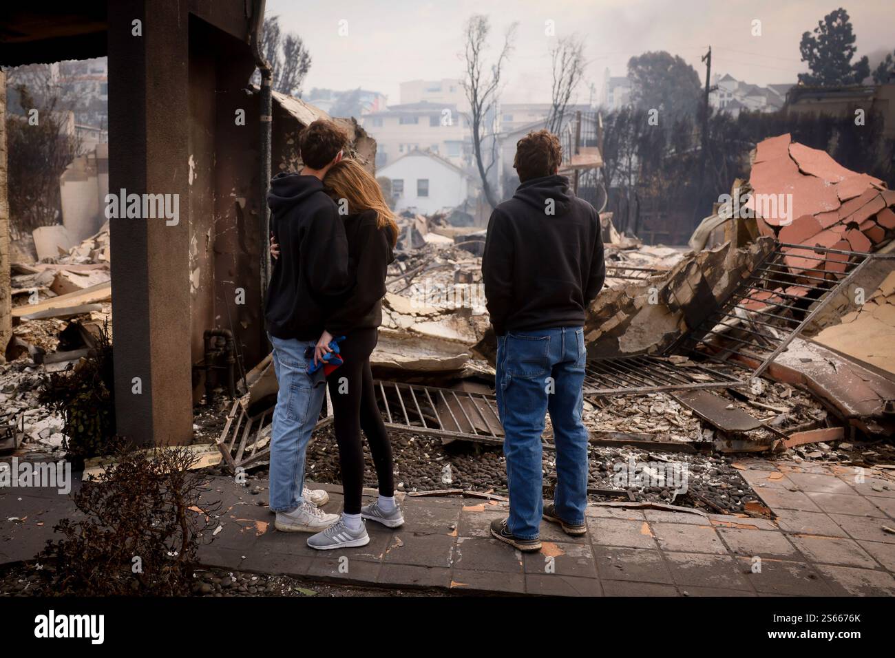 FILE - Residents embrace in front of a fire-ravaged property after the Palisades Fire swept ...