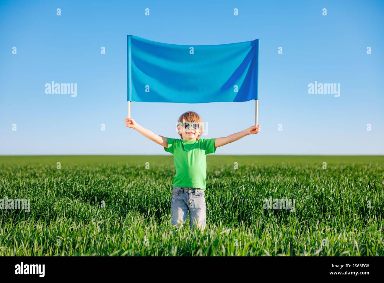 Happy child holding blue banner blank. Kid having fun outdoor in spring ...