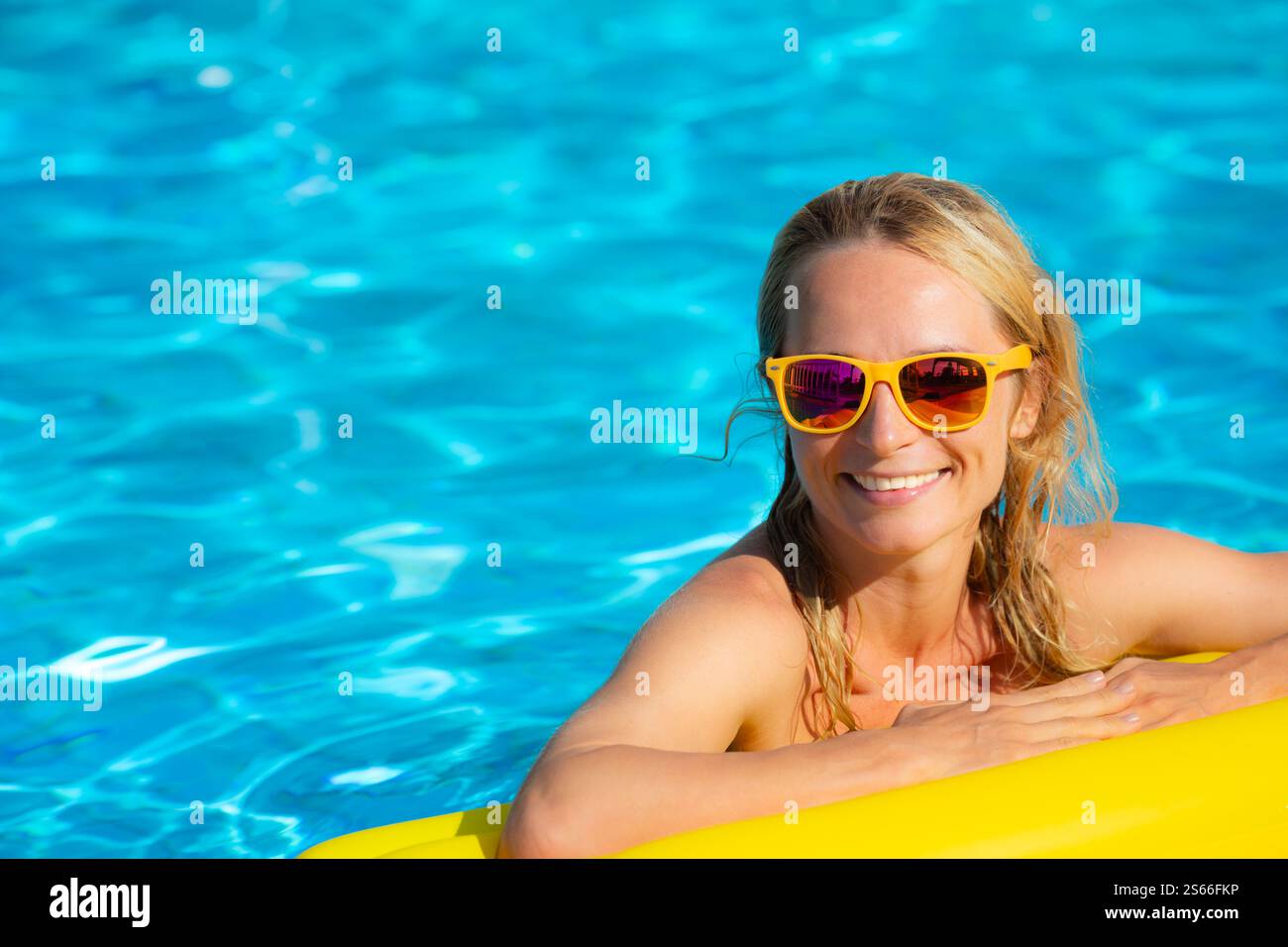Happy young woman having fun on summer vacation. Beautiful woman posing in swimming pool. Active ...