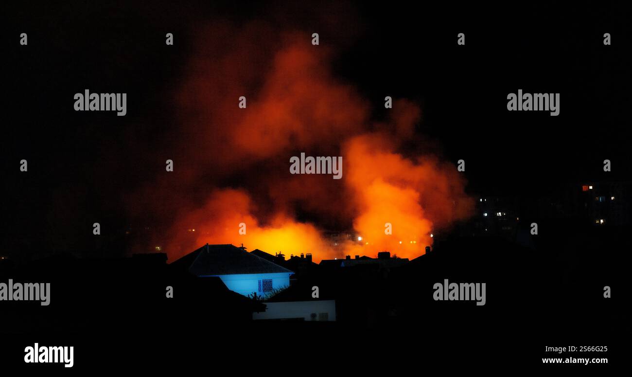 Night fire in residential area with cottage and high-rise buildings in ...