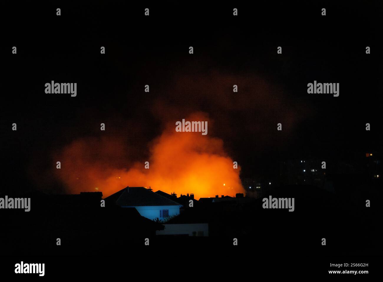Night fire in residential area with cottage and high-rise buildings in ...