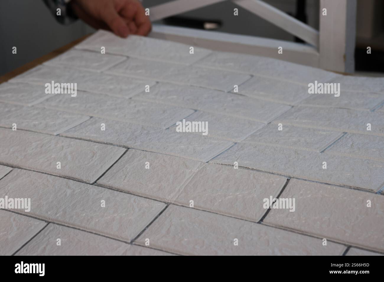 A woman is demonstrating self-adhesive wall panels. The panels have a ...