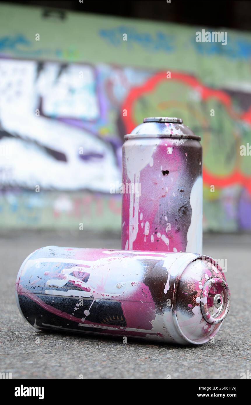 A few used spray cans with pink and white paint lie on the asphalt ...
