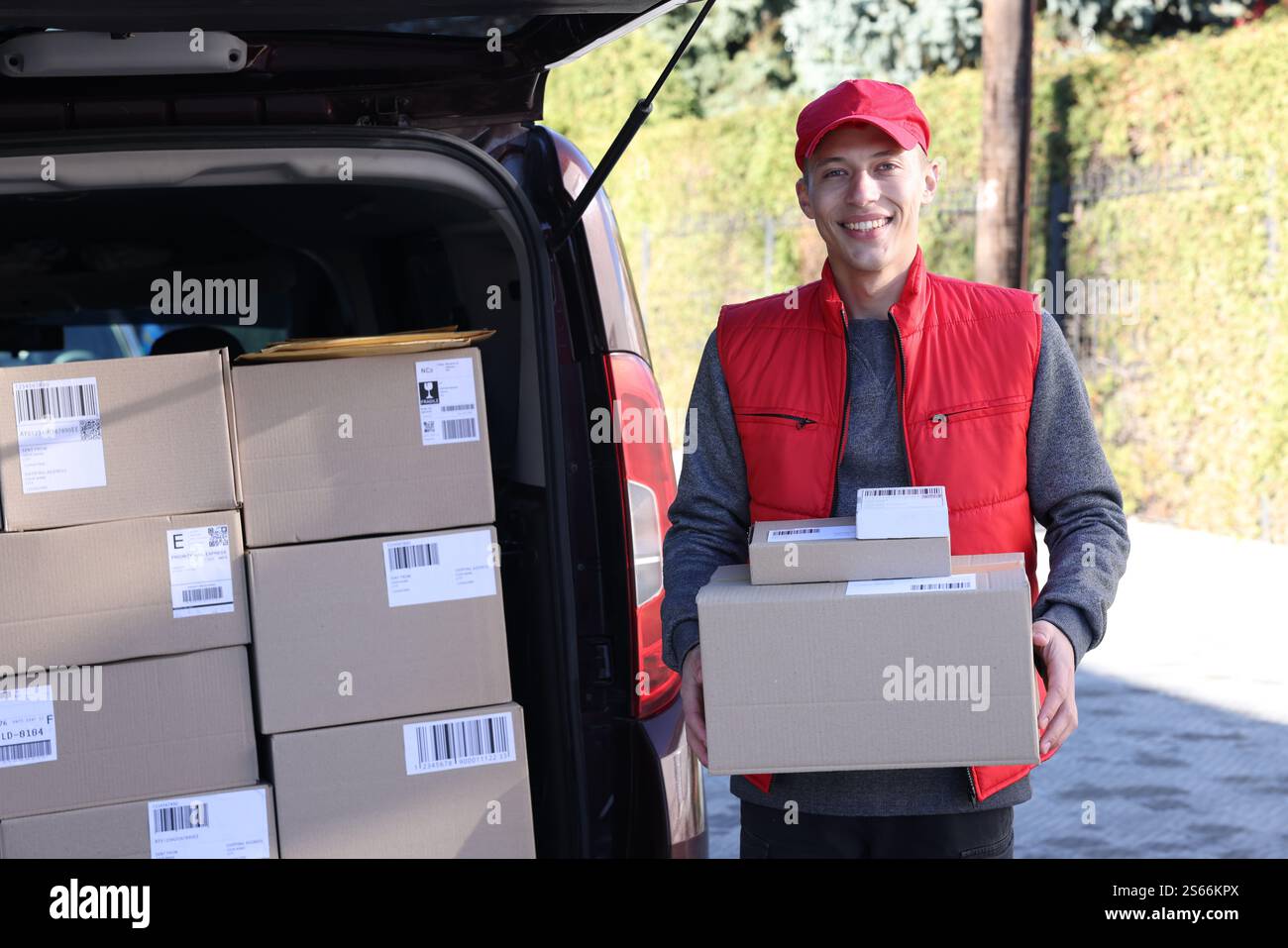 Happy postman with parcels near car outdoors Stock Photo - Alamy