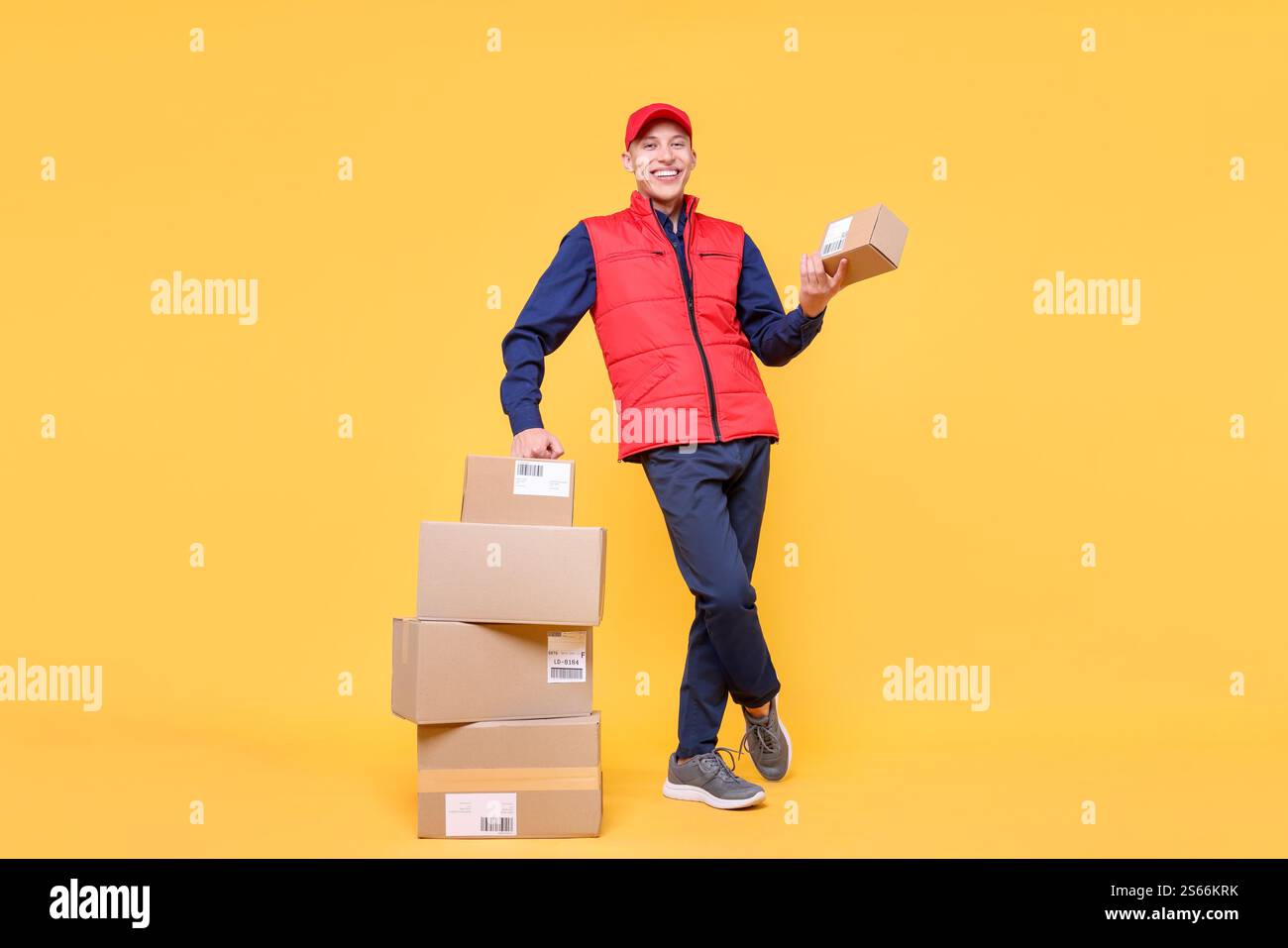 Happy postman with parcels on yellow background Stock Photo - Alamy
