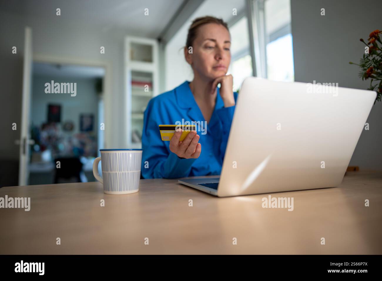 Focused woman on laptop uses credit card for online transaction, lost ...