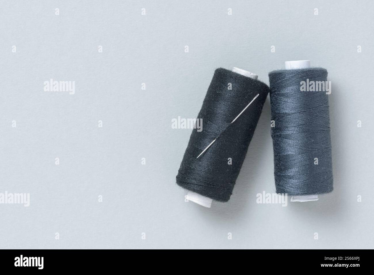 Black grey gray thread spools with needle background with copy space ...