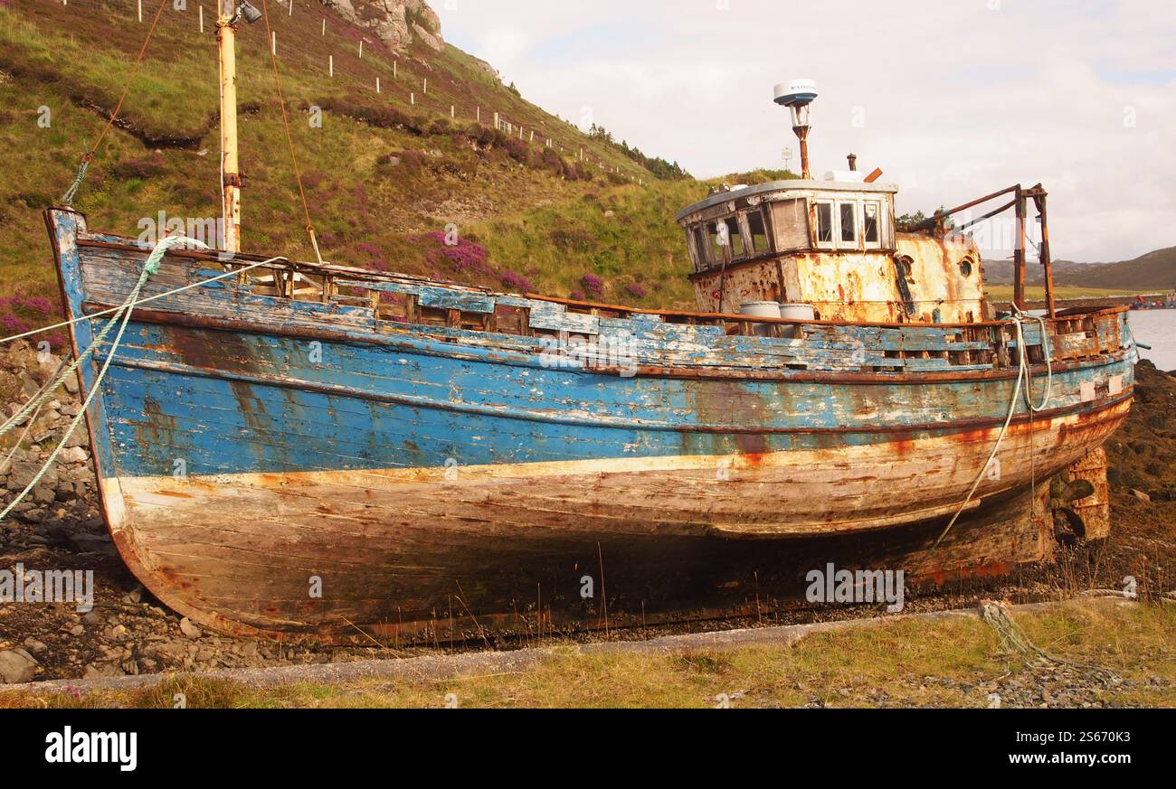 An abandoned, decaying, fishing vessel, out of the water, on the ...
