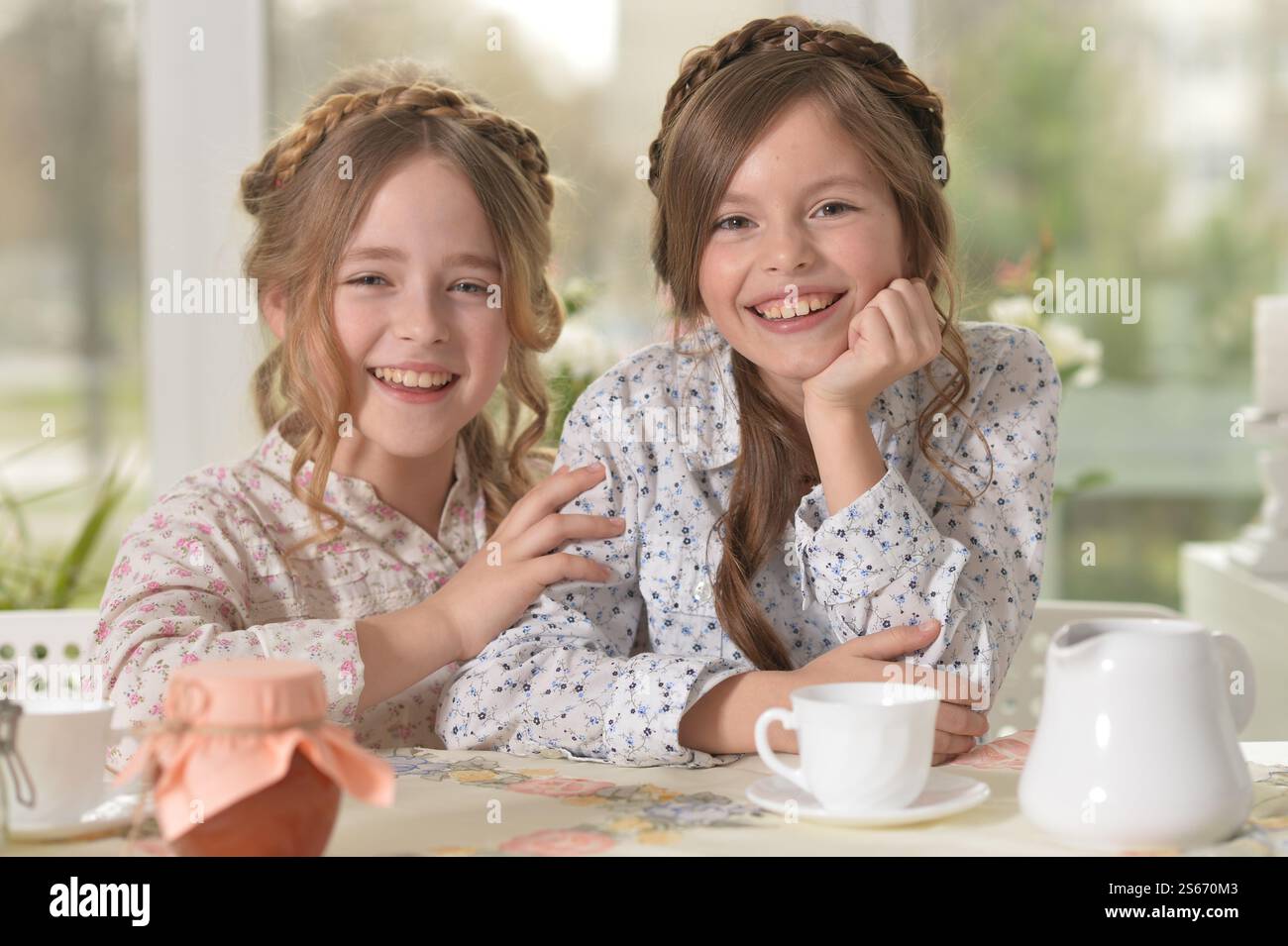 Portrait of two smiling little girls drinking tea at home Stock Photo ...