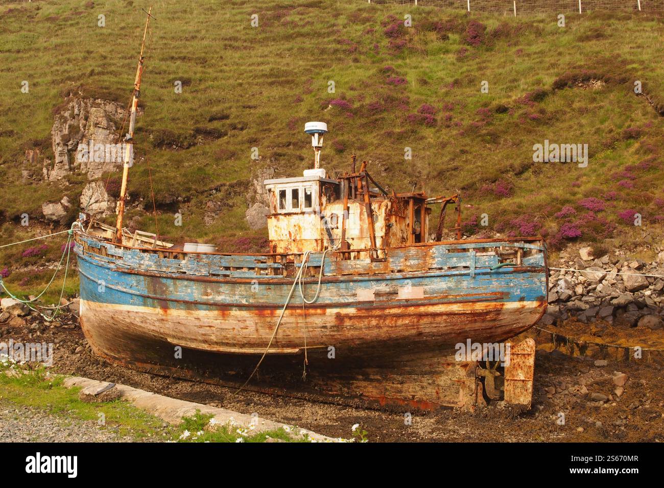An abandoned, decaying, fishing vessel, out of the water, on the ...