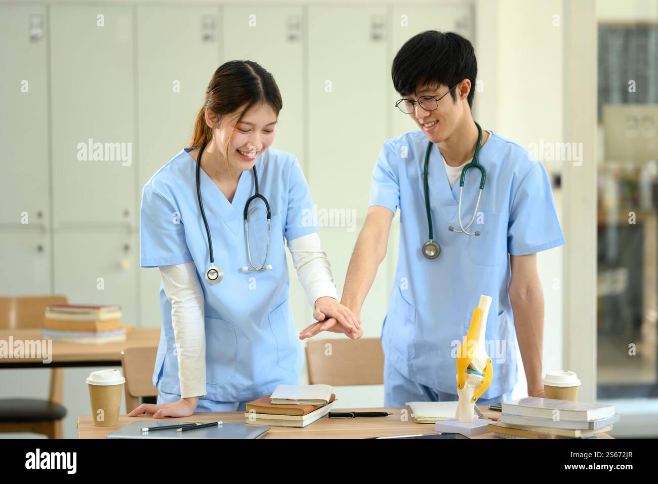 Medical students placing their hands together in a gesture of teamwork ...