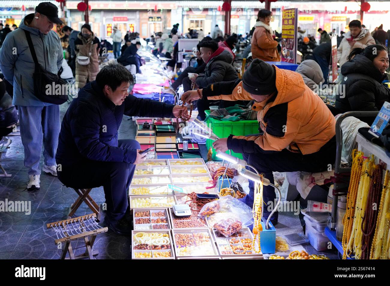 A man buys beads at a market in Beijing, Thursday, Jan. 16, 2025. (AP ...