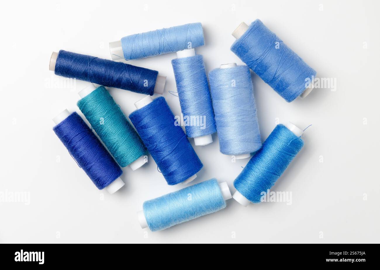 Blue thread spools on white background Stock Photo - Alamy