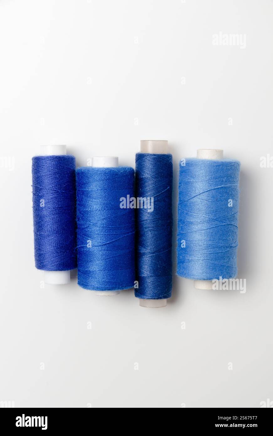 Blue thread spools on white background Stock Photo - Alamy