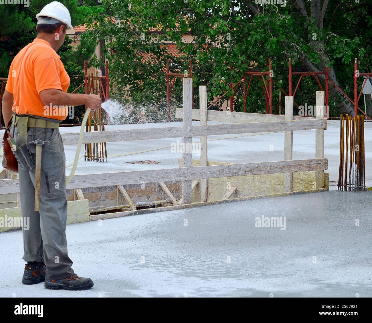 Construction carpenter waters the surface of a reinforced concrete ...
