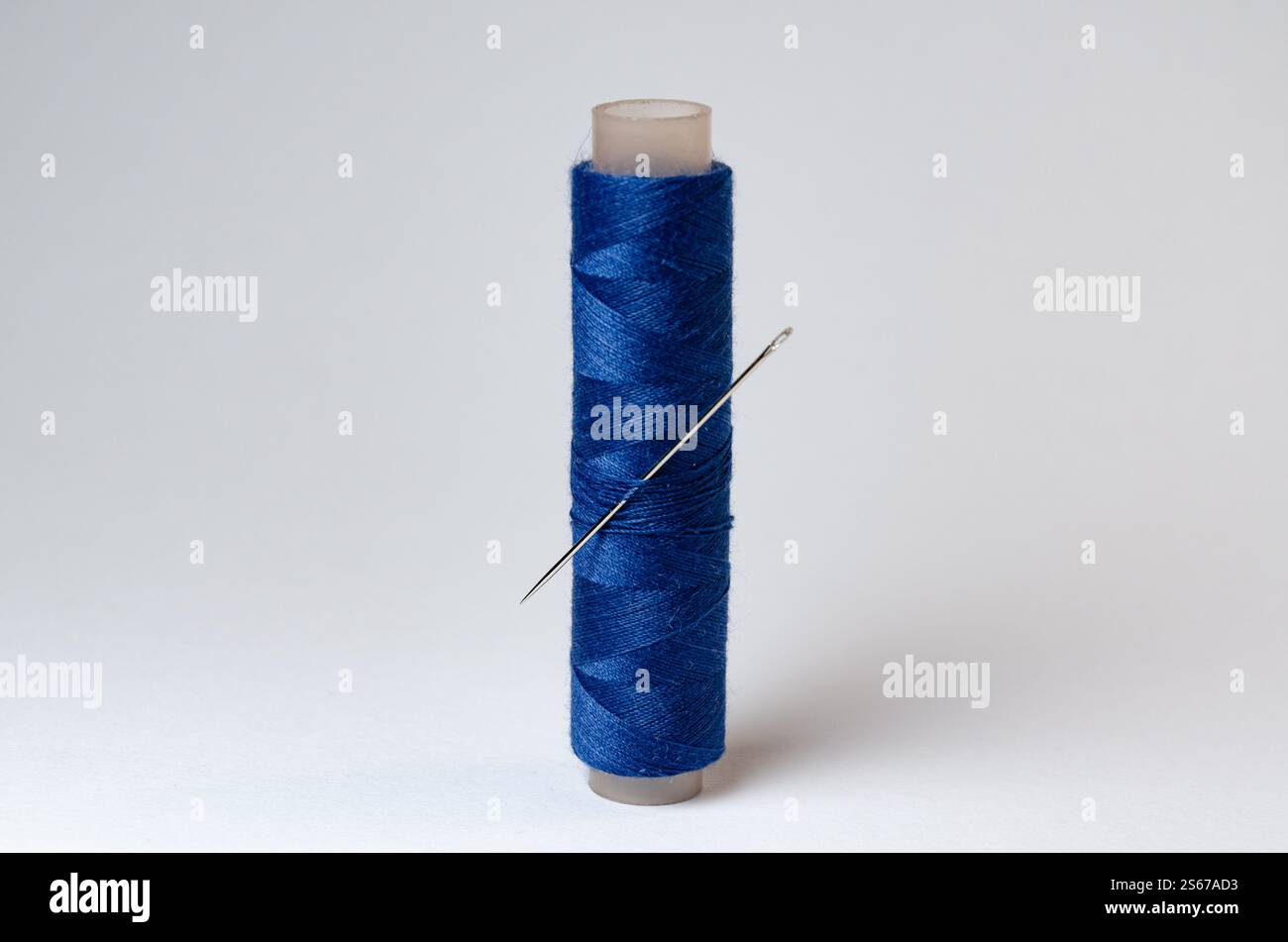 One single dark blue thread spool with needle on white background Stock ...