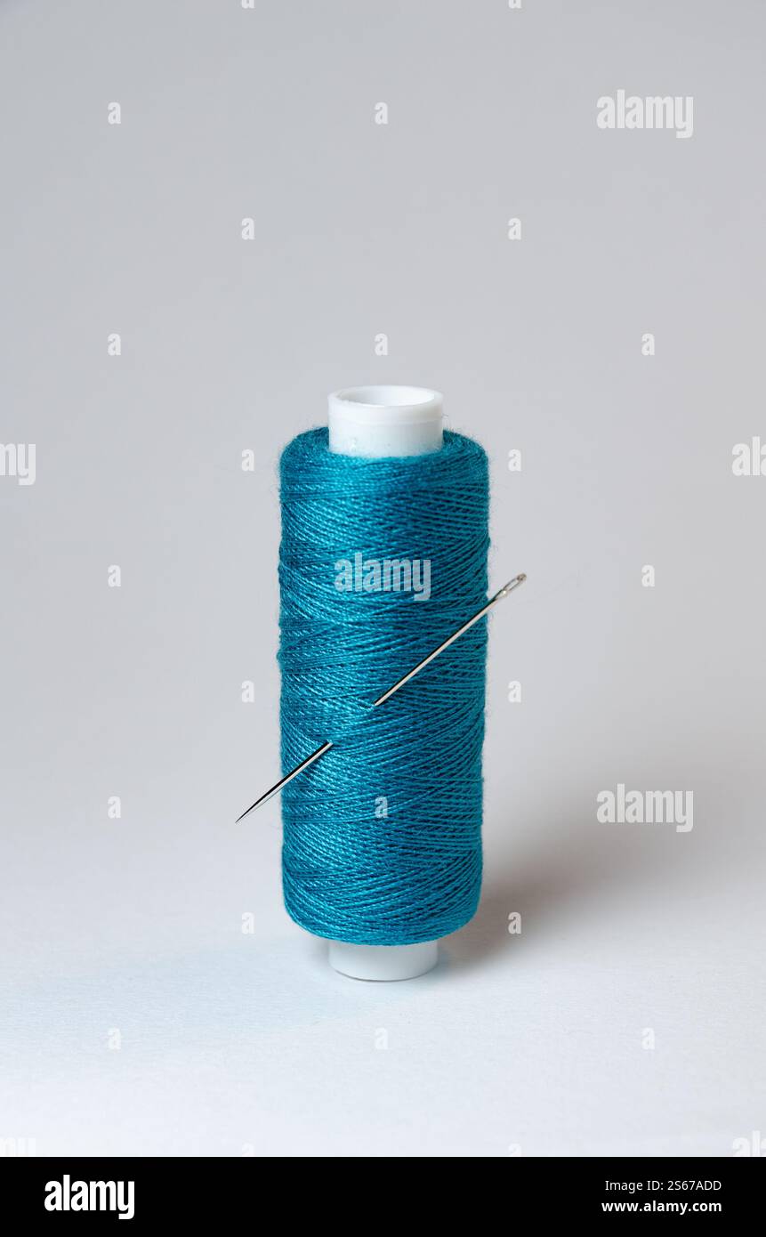 One single turquoise thread spool with needle on white background Stock ...