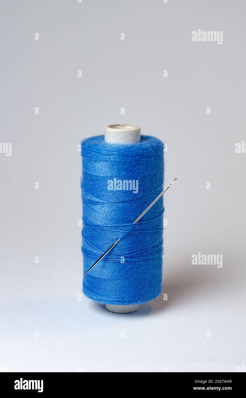 One single blue thread spool with needle on white background Stock ...