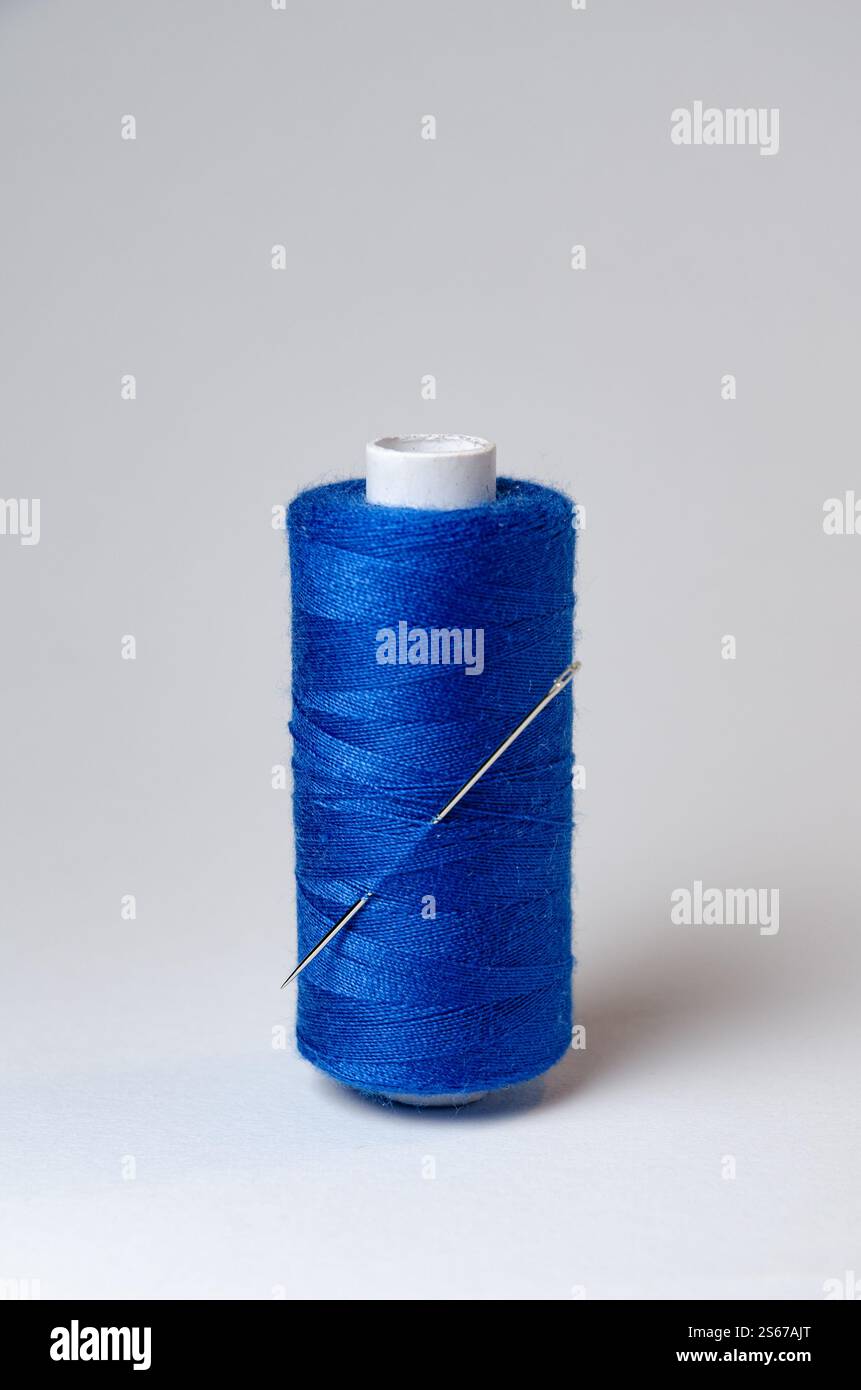One single dark blue thread spool with needle on white background Stock ...