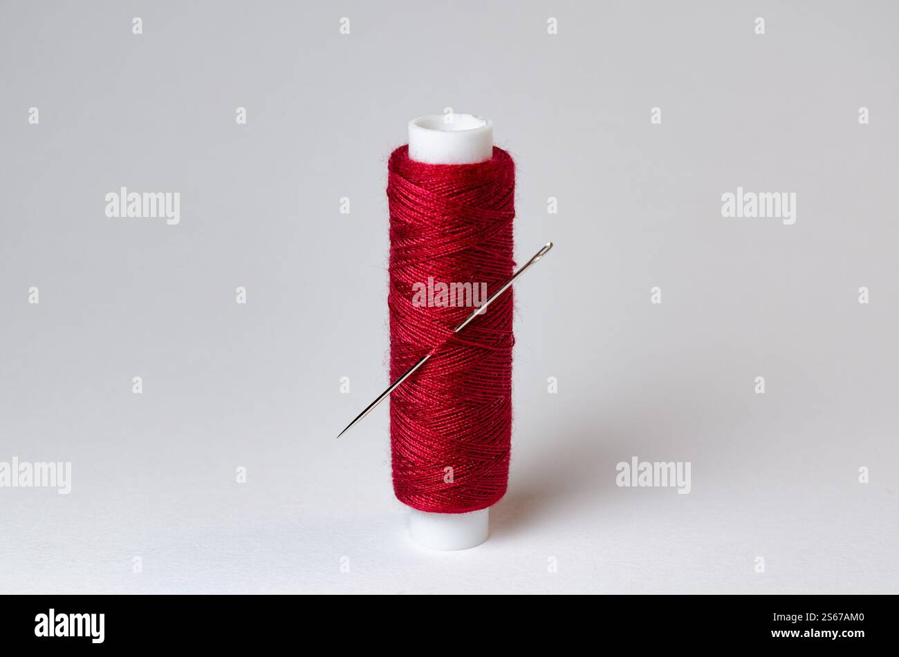 One single red thread spool with needle on white background Stock Photo ...