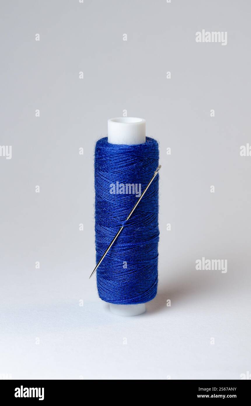 One single dark blue thread spool with needle on white background Stock ...