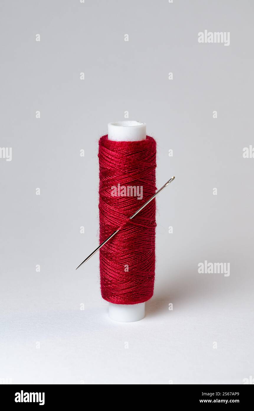 One single red thread spool with needle on white background Stock Photo ...