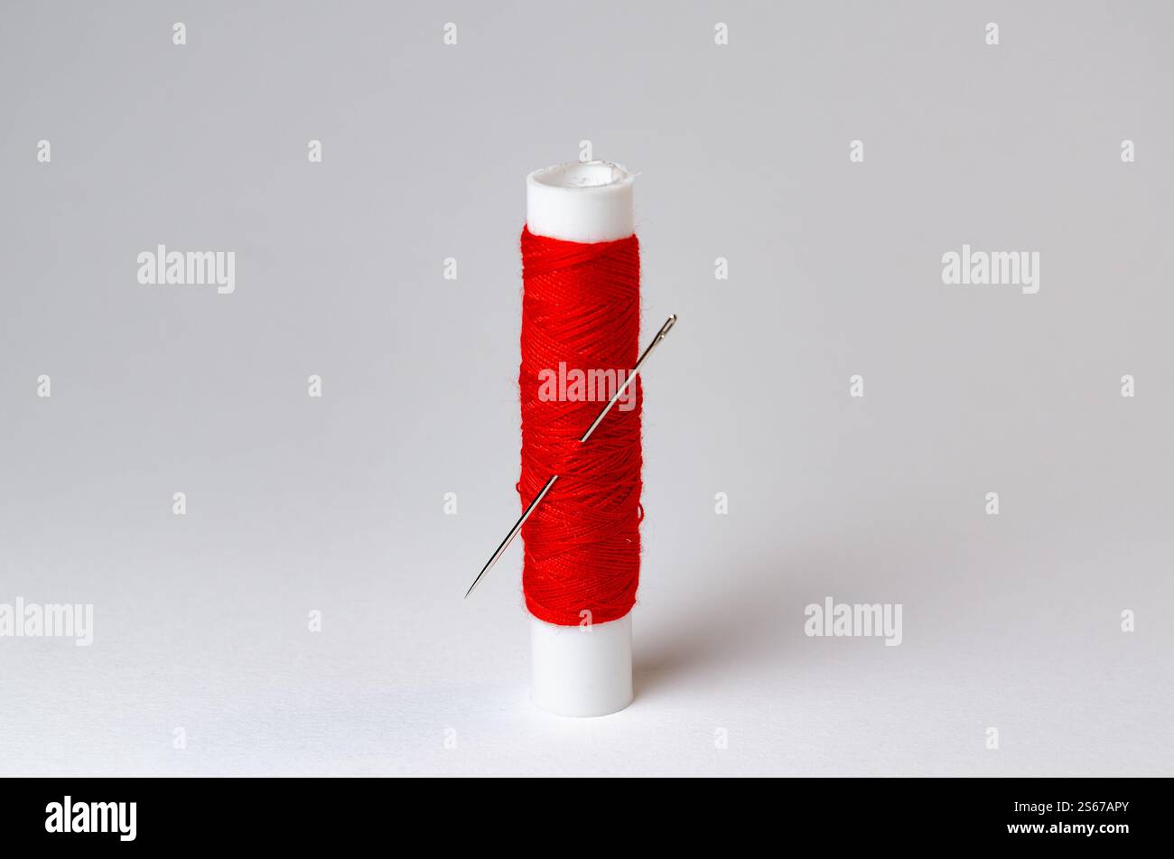 One single red thread spool with needle on white background Stock Photo ...