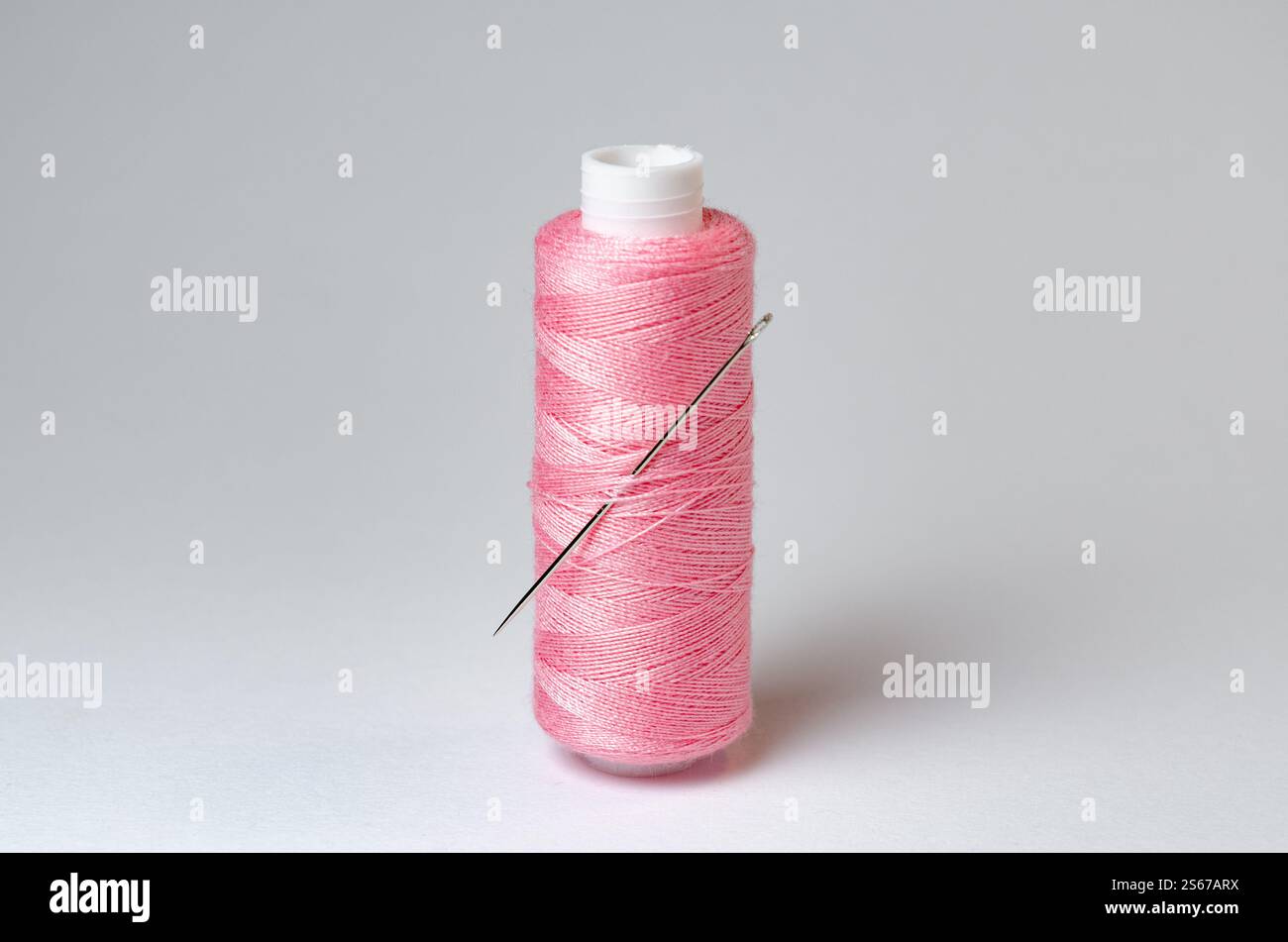 One single pink thread spool with needle on white background Stock ...
