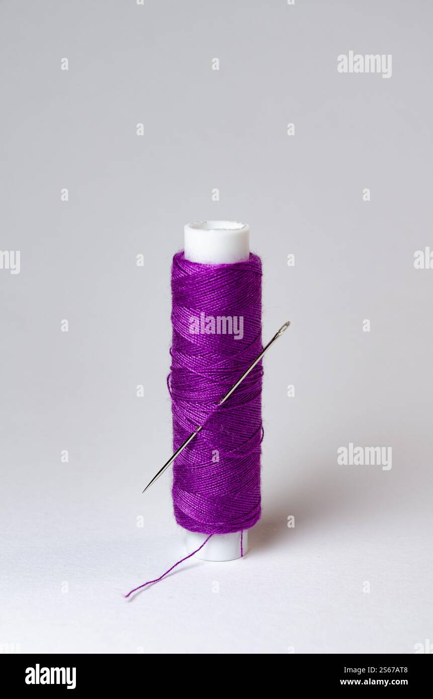 One single purple thread spool with needle on white background Stock ...