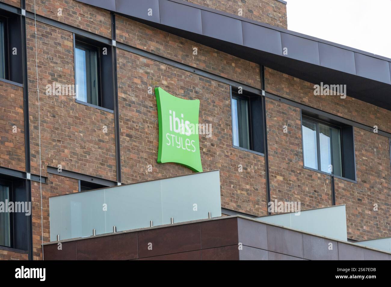 Green ibis styles logo is attached to a brick wall of a modern hotel ...