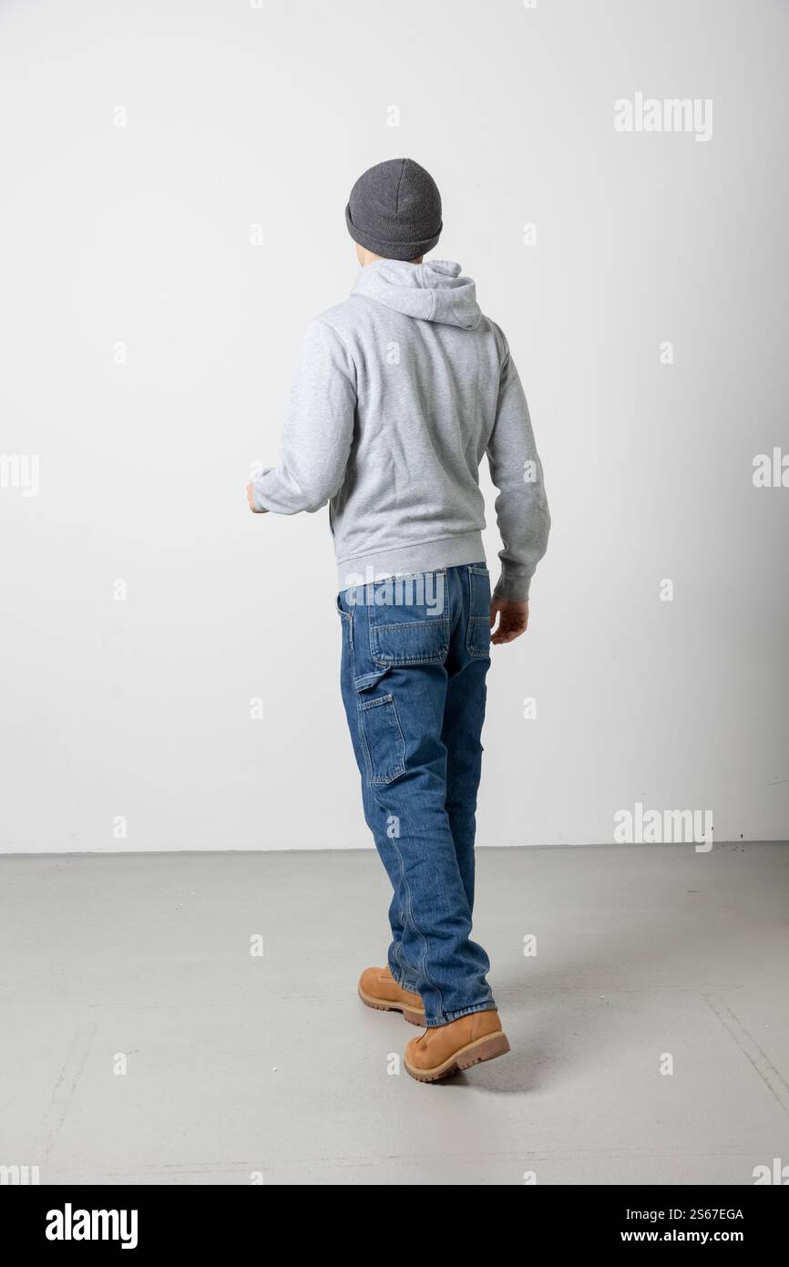 Young boy seen from behind standing on a white background in one piece ...