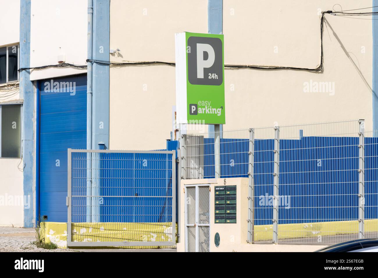 Green parking sign indicating 24 hour parking availability in front of an industrial building ...