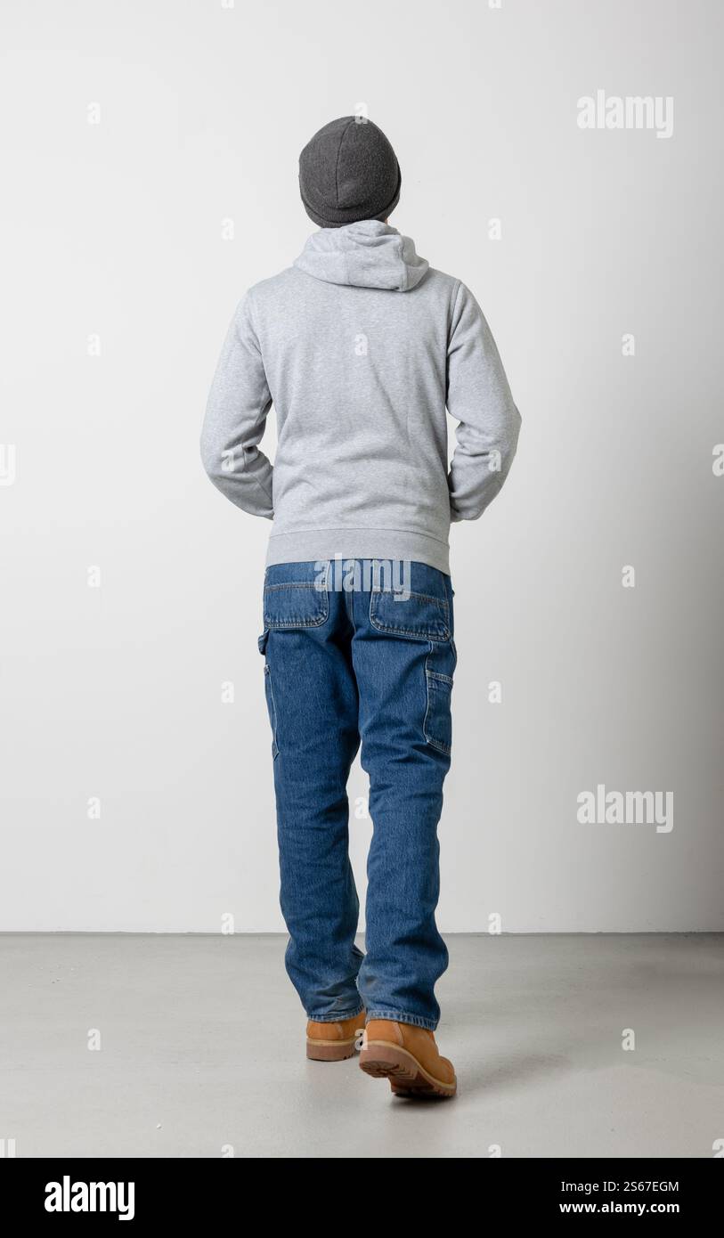 Young boy seen from behind full body walks. White background. Hands in ...