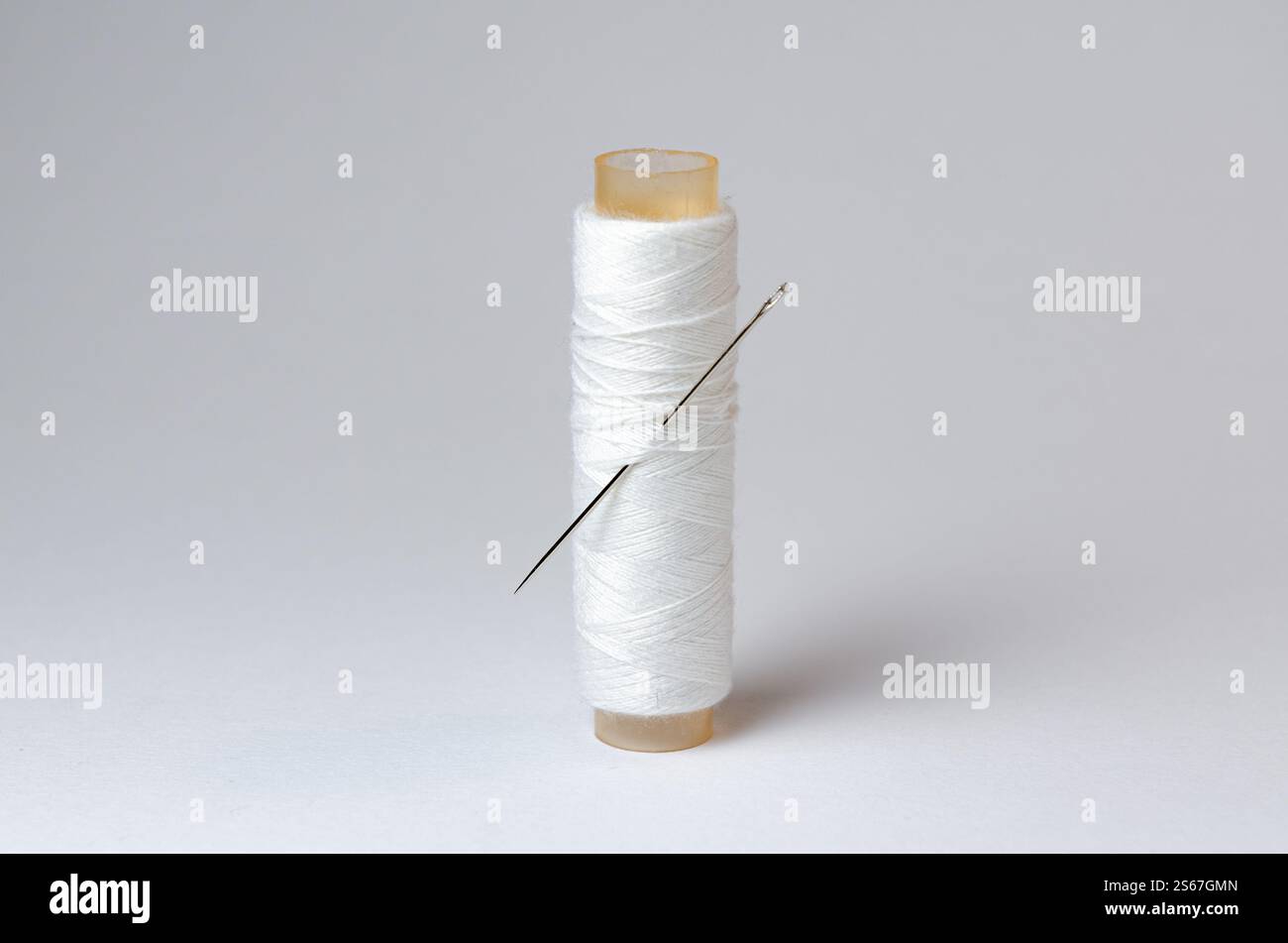 One single thread spool with needle on white background Stock Photo - Alamy
