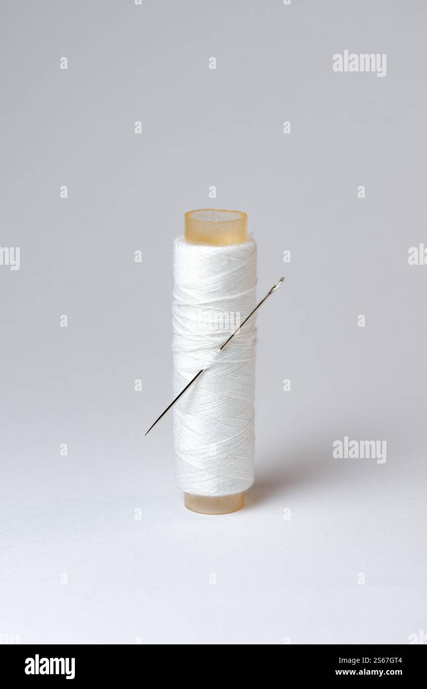 One single thread spool with needle on white background Stock Photo - Alamy