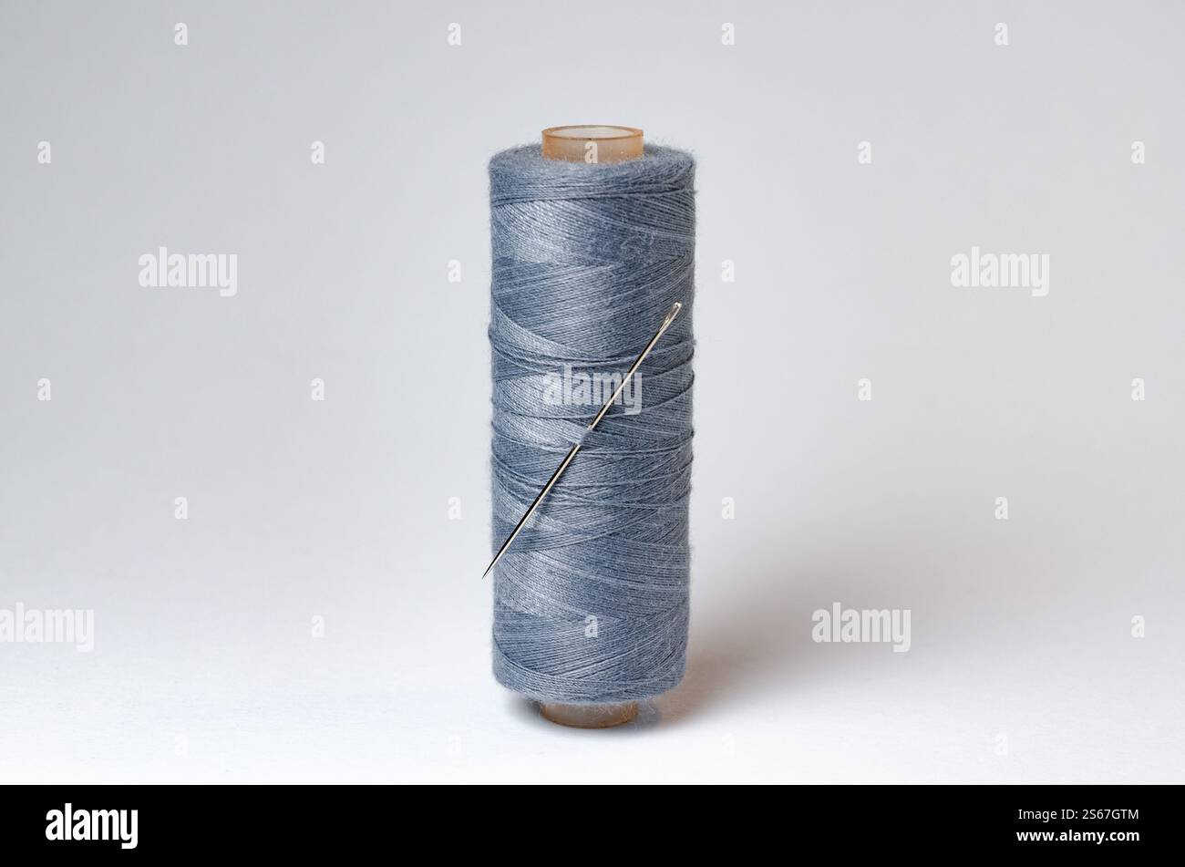 One single grey thread spool with needle on white background Stock ...