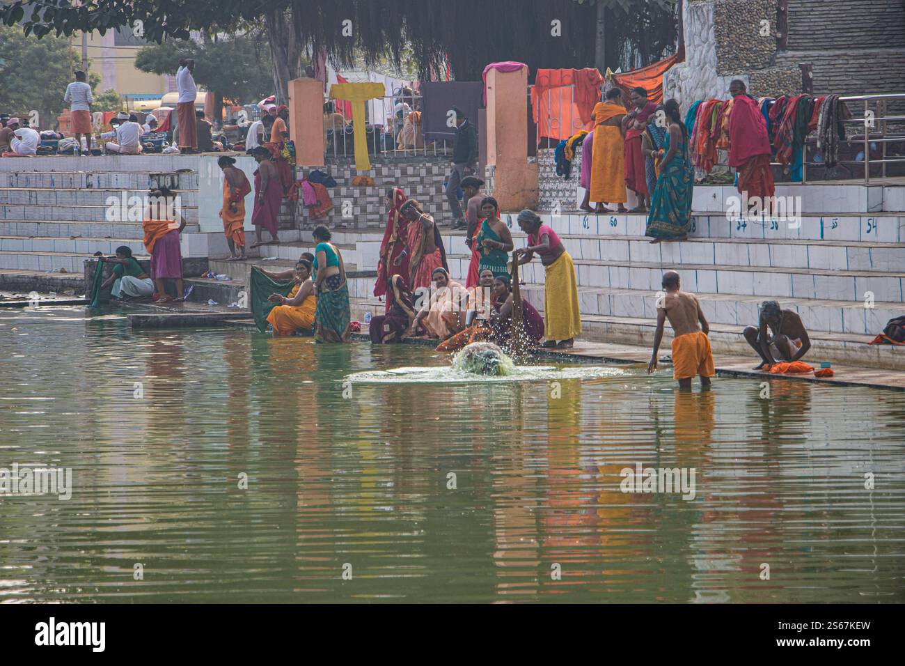 Life at Dhanushsagar Pond. Pilgrims bathing, washing clothes, and ...