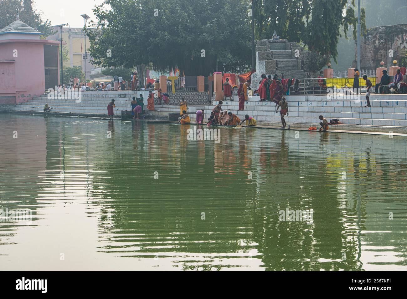 Life at Dhanushsagar Pond. Pilgrims bathing, washing clothes, and ...