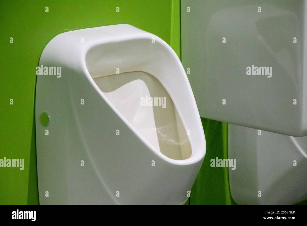 A white urinal with yellow liquid inside attached to a bright green ...
