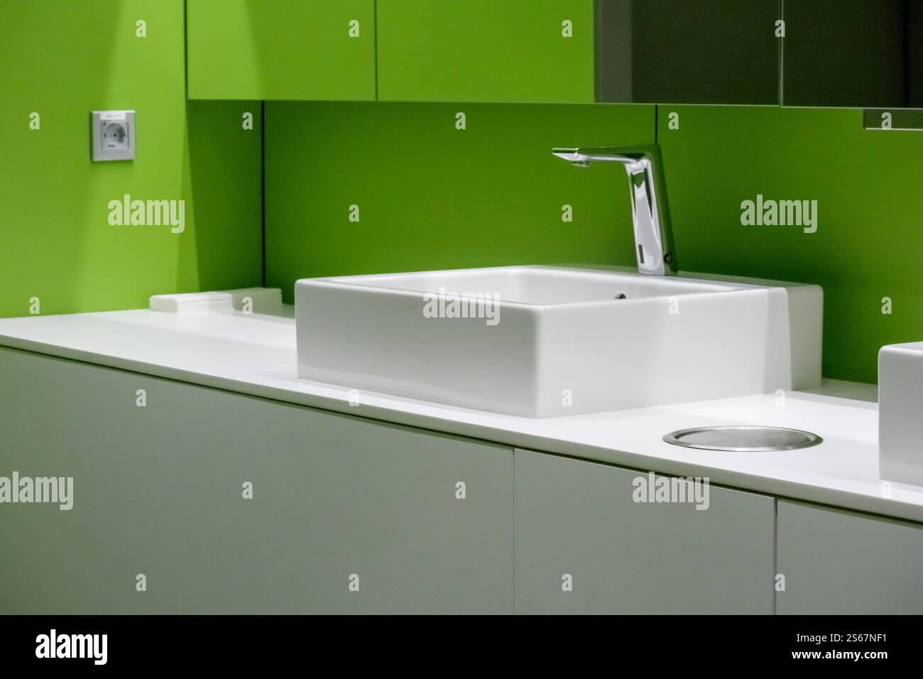 A white, square basin with a chrome mixer, mounted on a white worktop ...