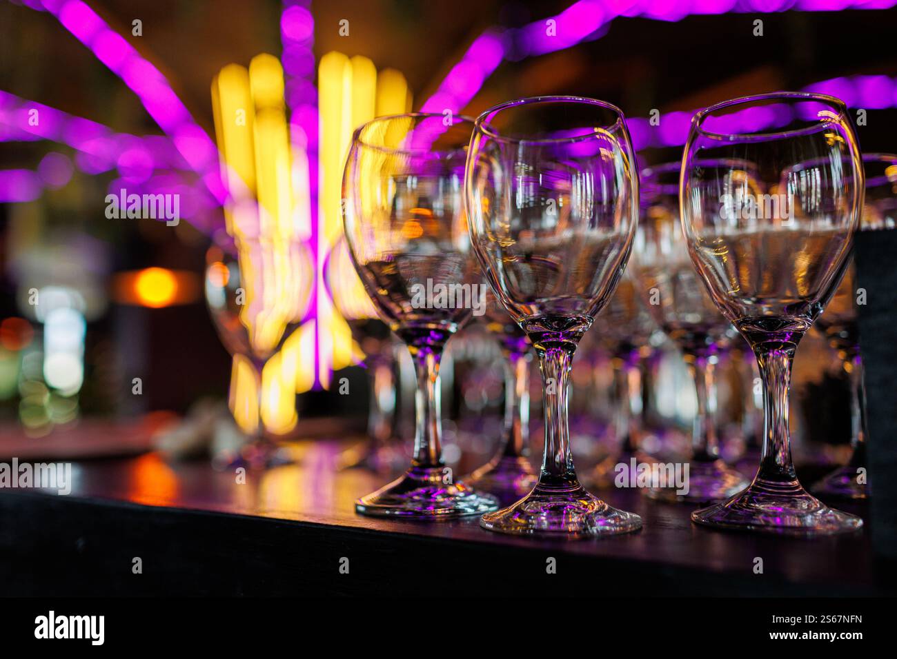 Empty clear wineglasses stand in rows on bar counter at nightclub ...