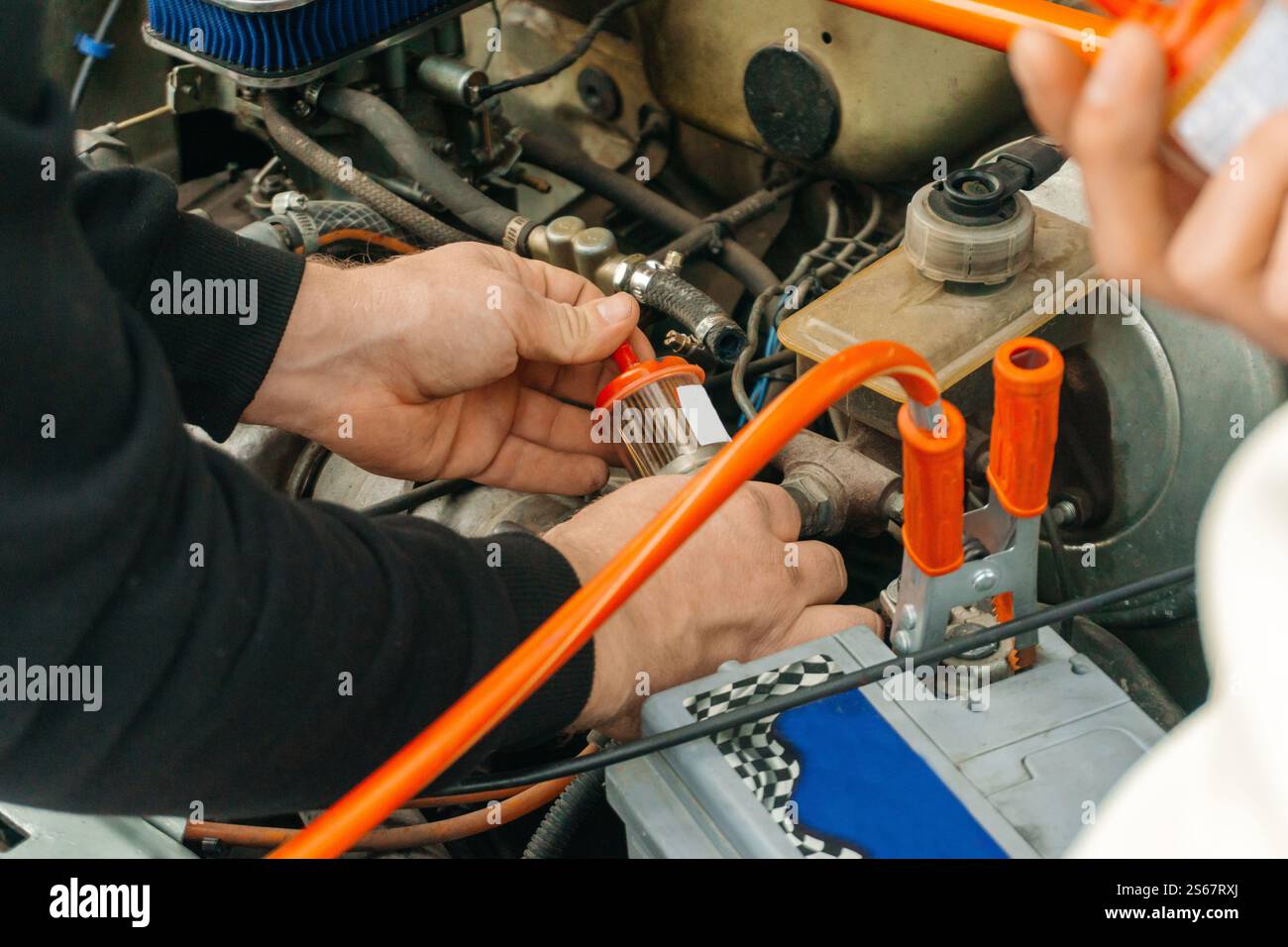 two men are repairing a car on the road. replacing the fuel filter ...