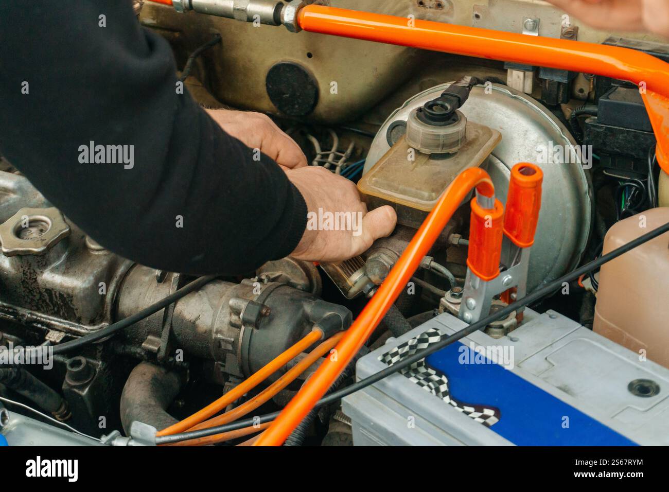 two men are repairing a car on the road. replacing the fuel filter ...