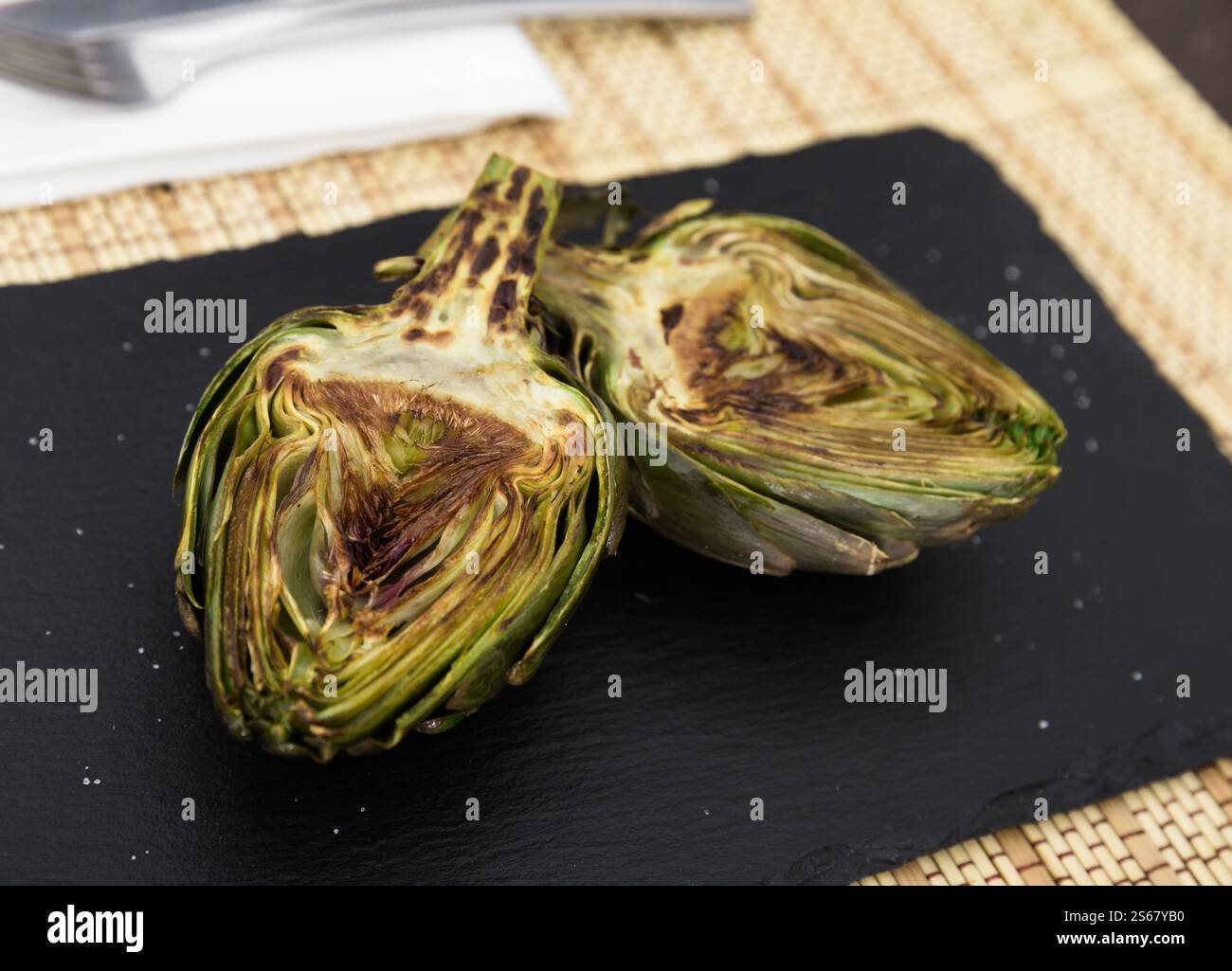 Cooked fried halves artichokes on black stone board Stock Photo - Alamy