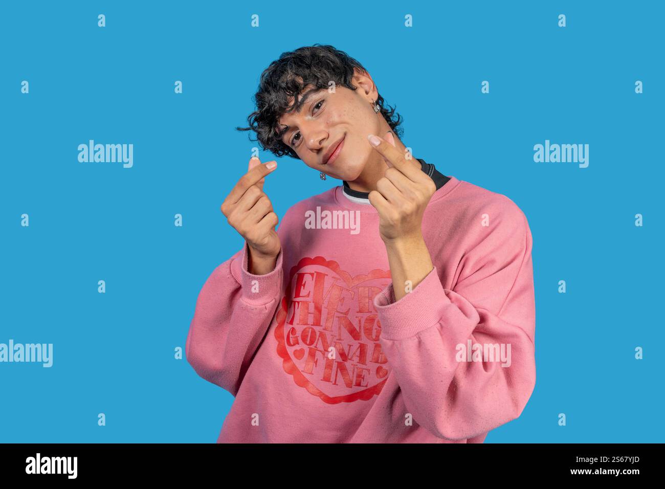 Cheerful young man making korean finger heart sign, expressing love and ...